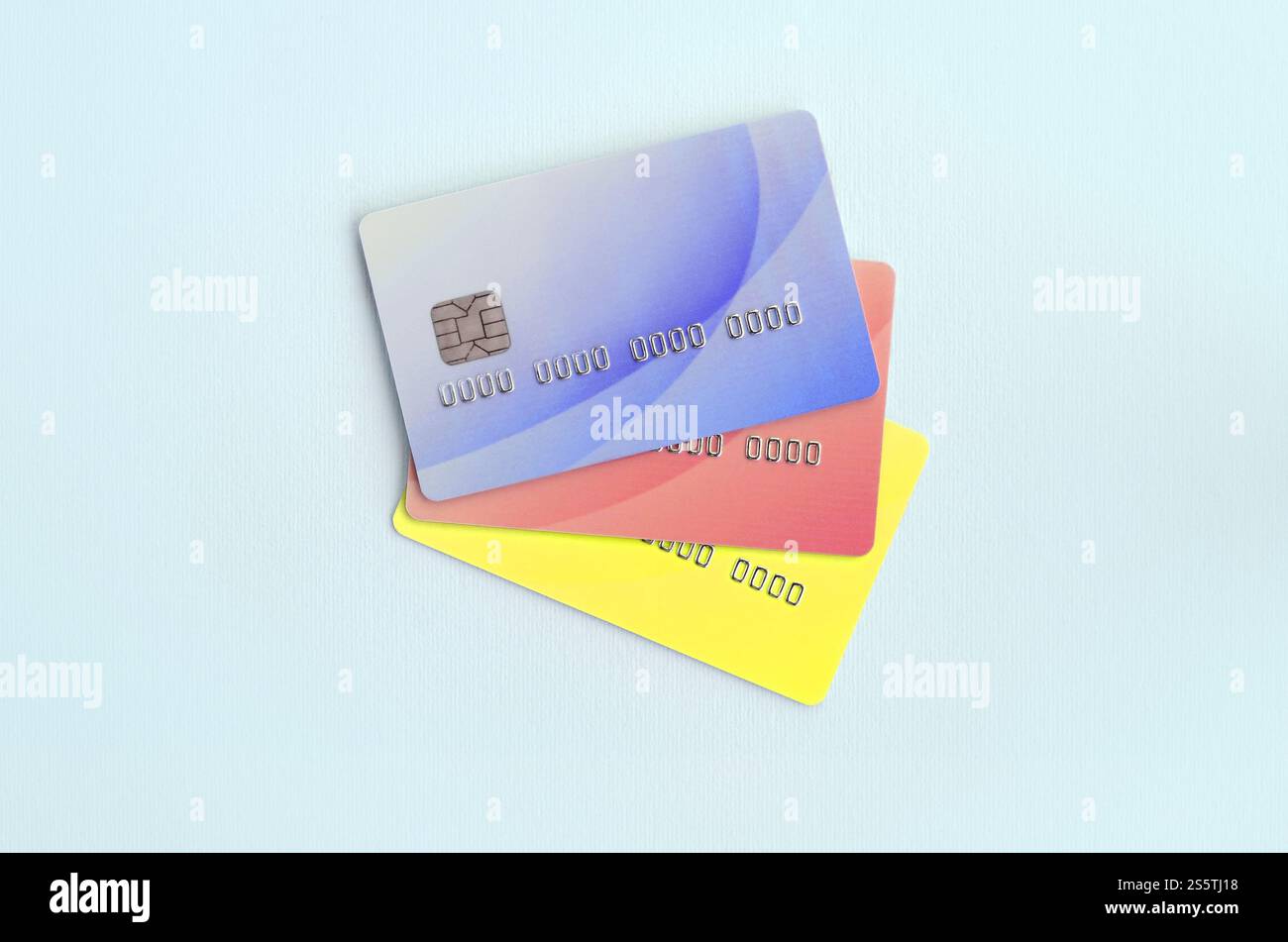Three colored credit cards lay on a pastel blue background. The concept ...
