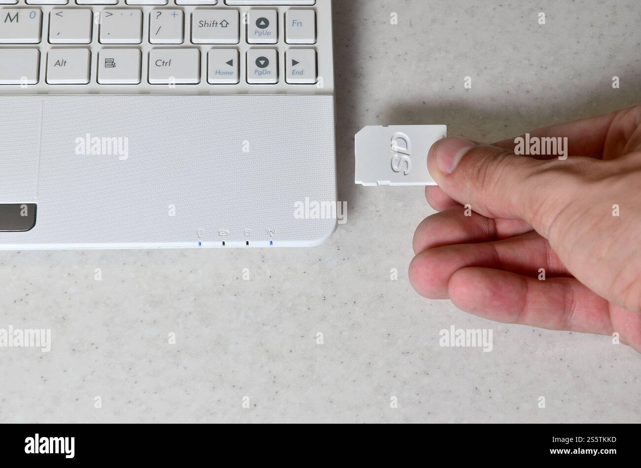 A male hand inserts a white compact SD card into the corresponding ... A male hand inserts a white compact SD card into the corresponding ...