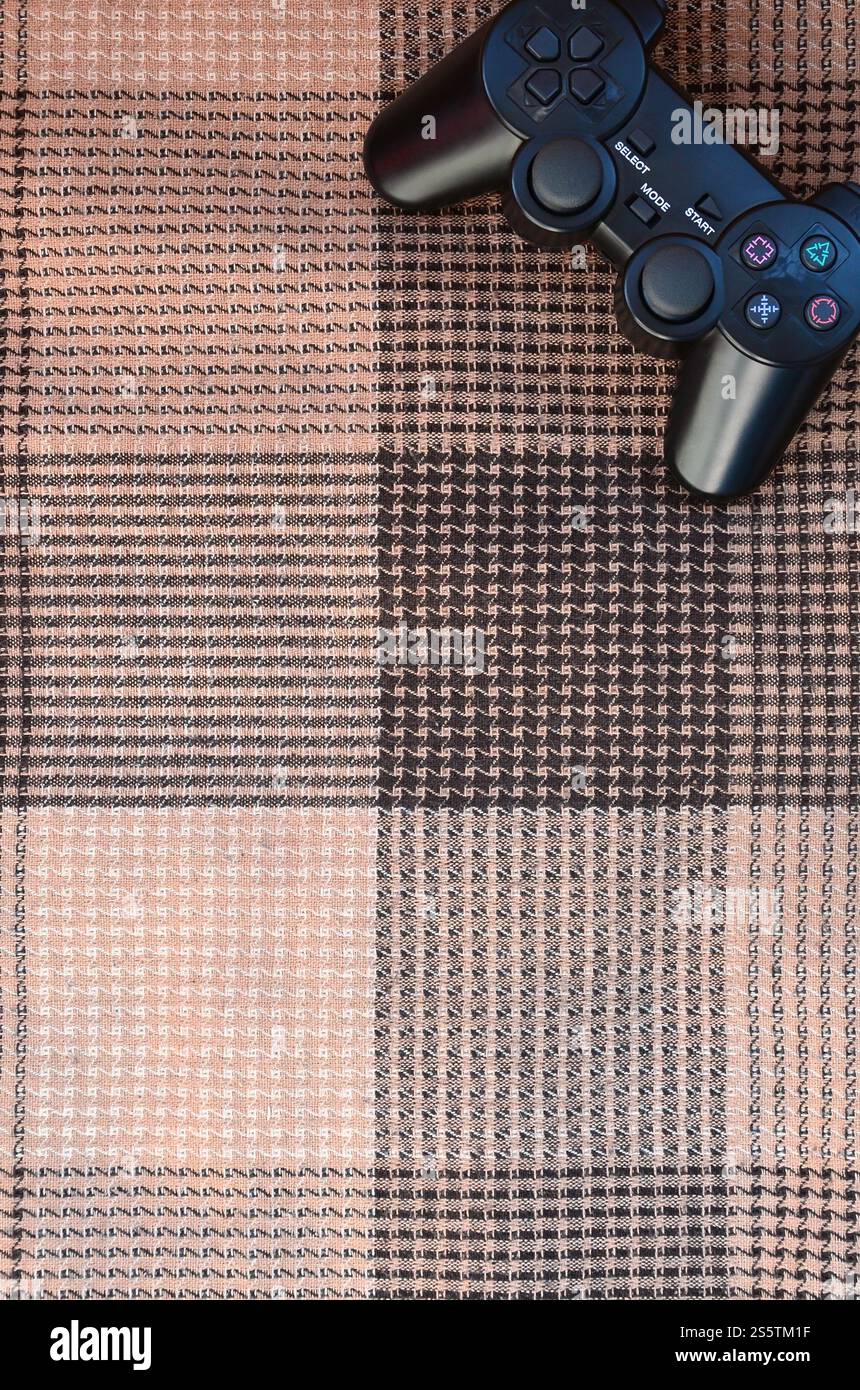 Modern black video game controller lies on a checkered beige and black ...
