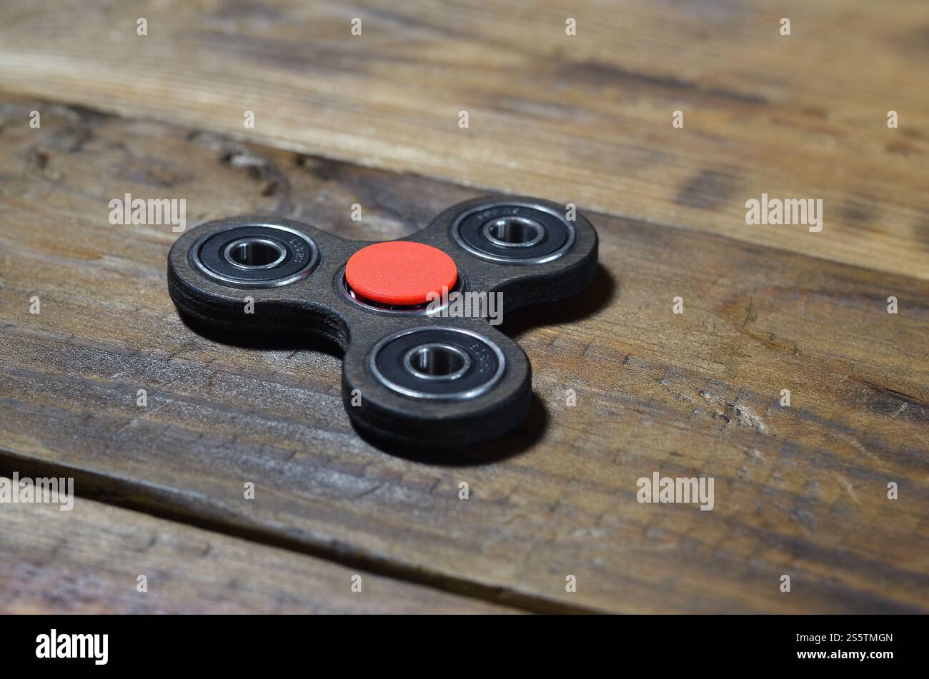 A rare handmade wooden fidget spinner lies on a brown wooden background ...