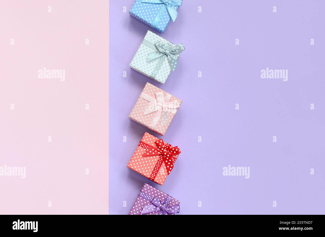 Small gift boxes of different colors with ribbons lies on a violet and ...