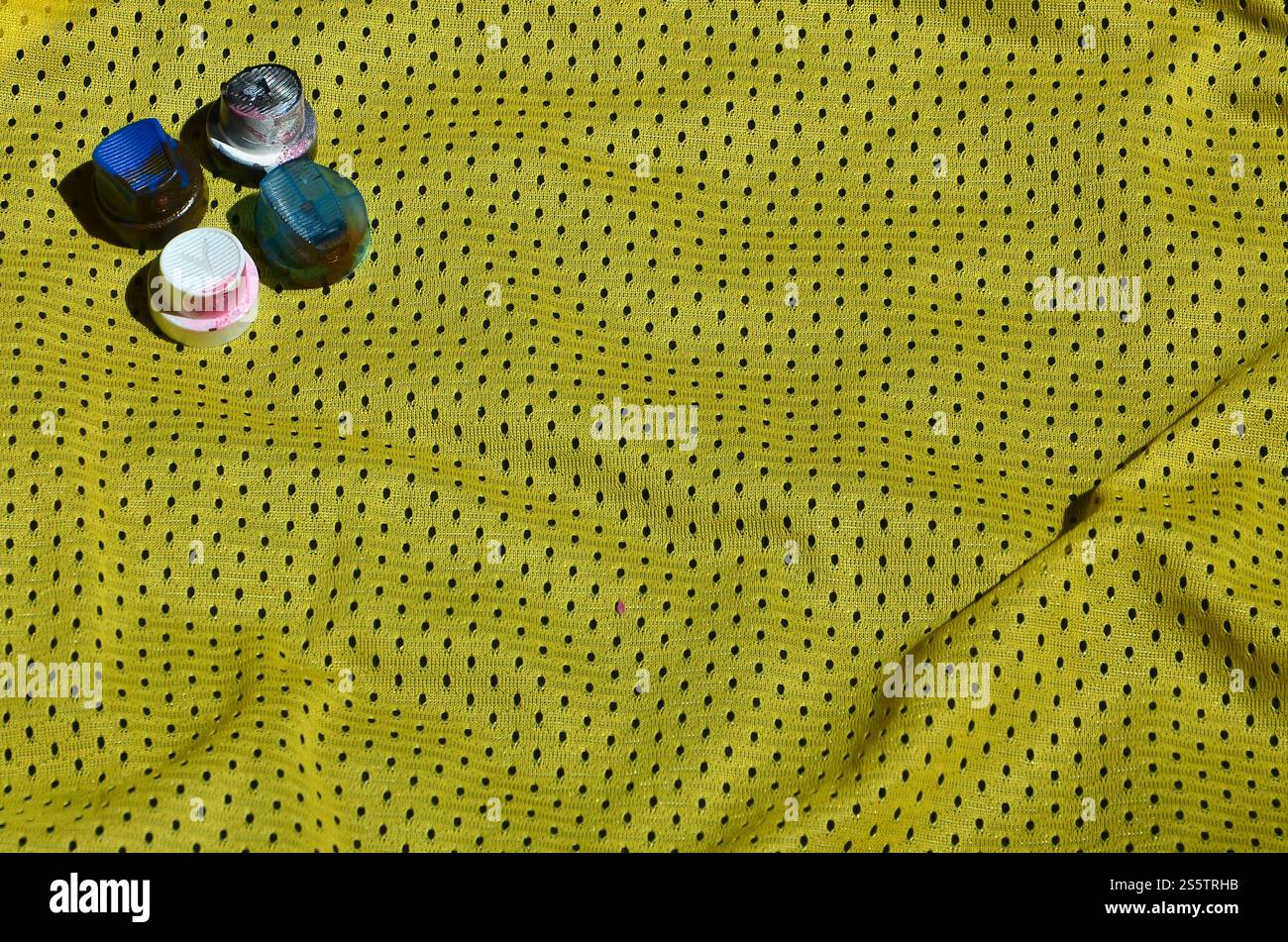 Several caps for used aerosol paint sprayers lie on the sports shirt of ...