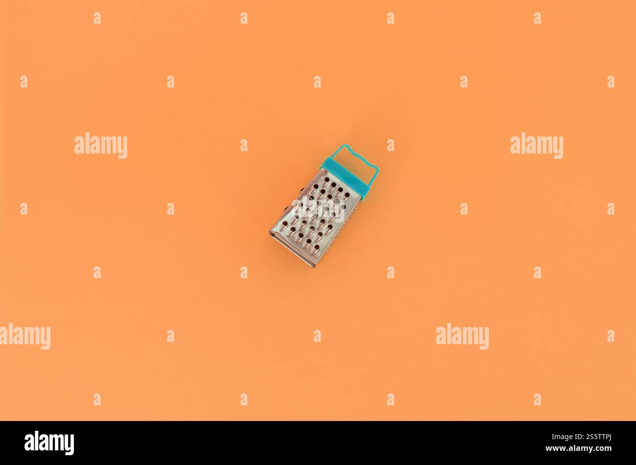 Stainless steel grater lies on a pastel colored paper. Kitchen ...