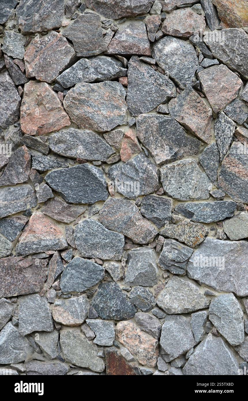 The texture of a strong stone wall of many concreted stones of various ...