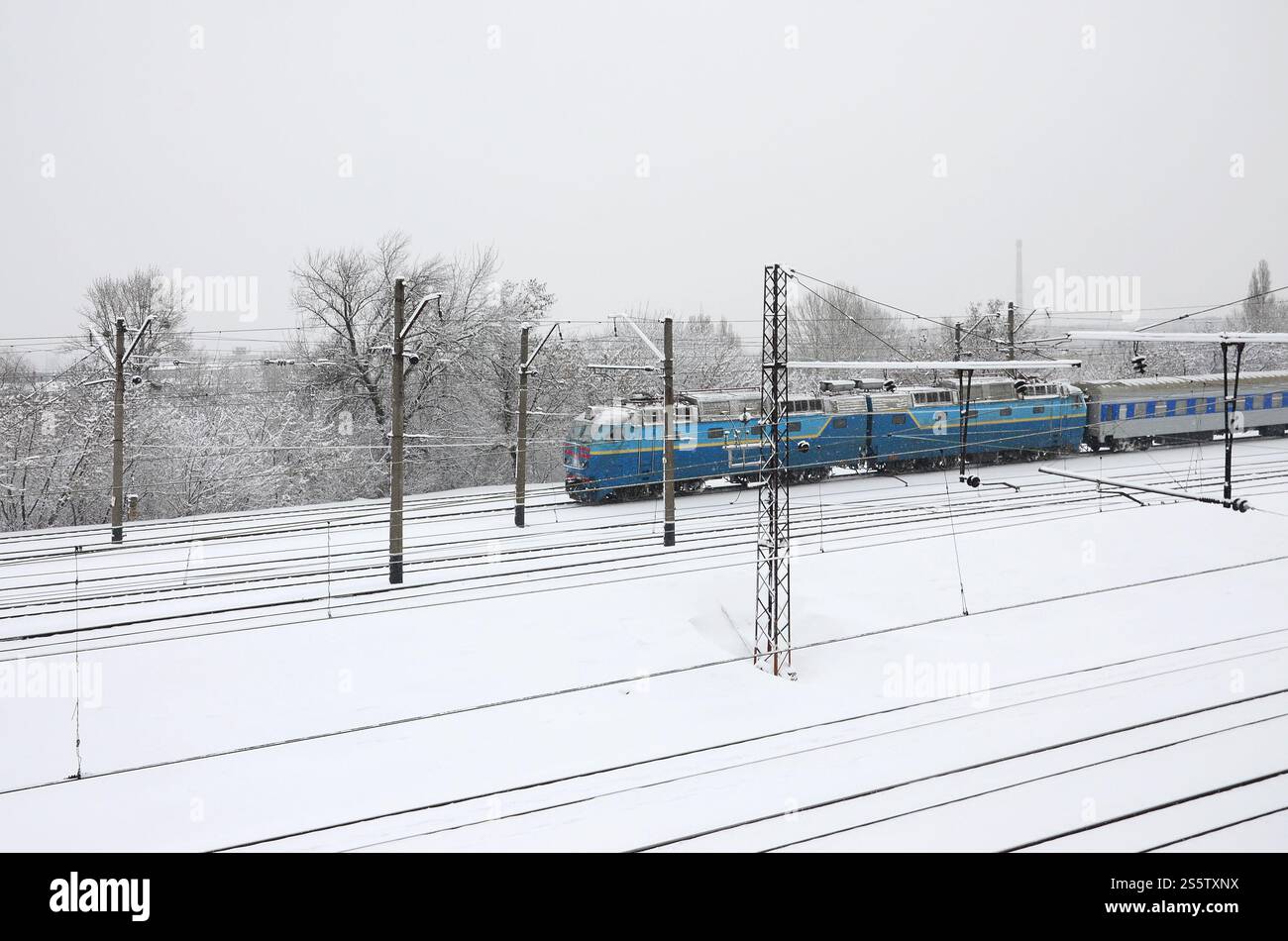 A long train of passenger cars is moving along the railway track ...