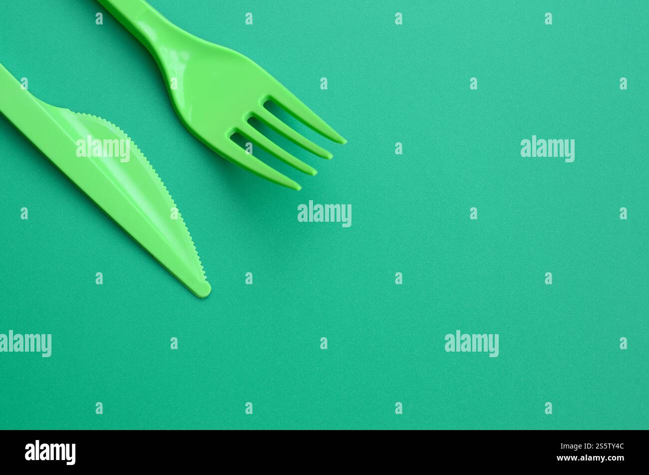 Disposable plastic cutlery green. Plastic fork and knife lie on a green ...