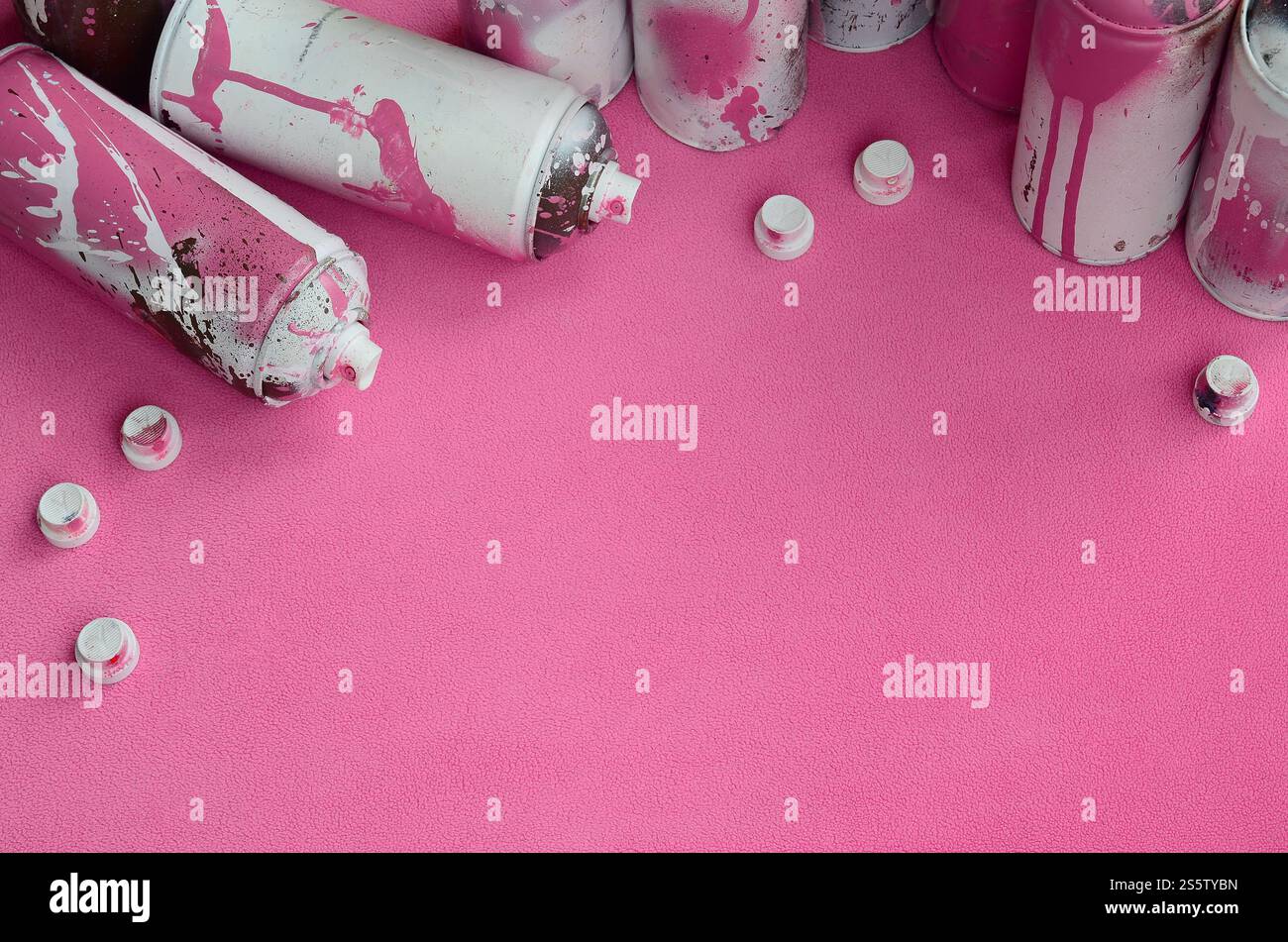 Some used pink aerosol spray cans and nozzles with paint drips lies on ...