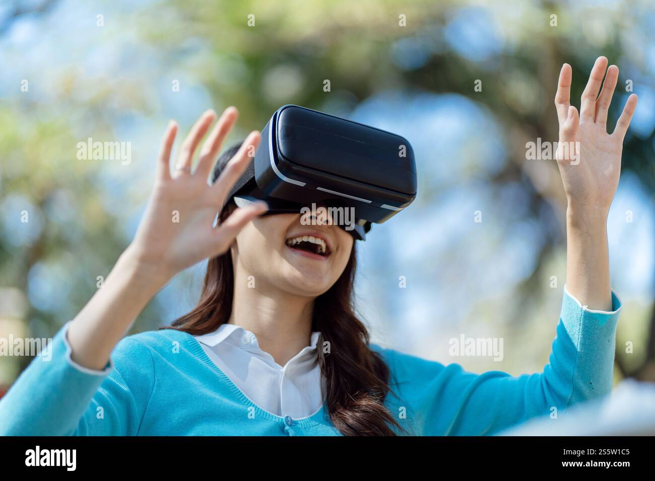 Young Asian woman gamer wearing virtual reality touching air during the VR experience Future ...
