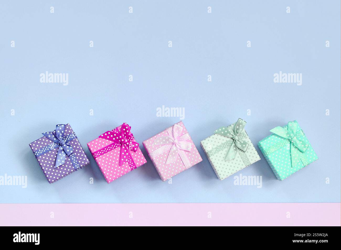 Small gift boxes of different colors with ribbons lies on a violet and ...