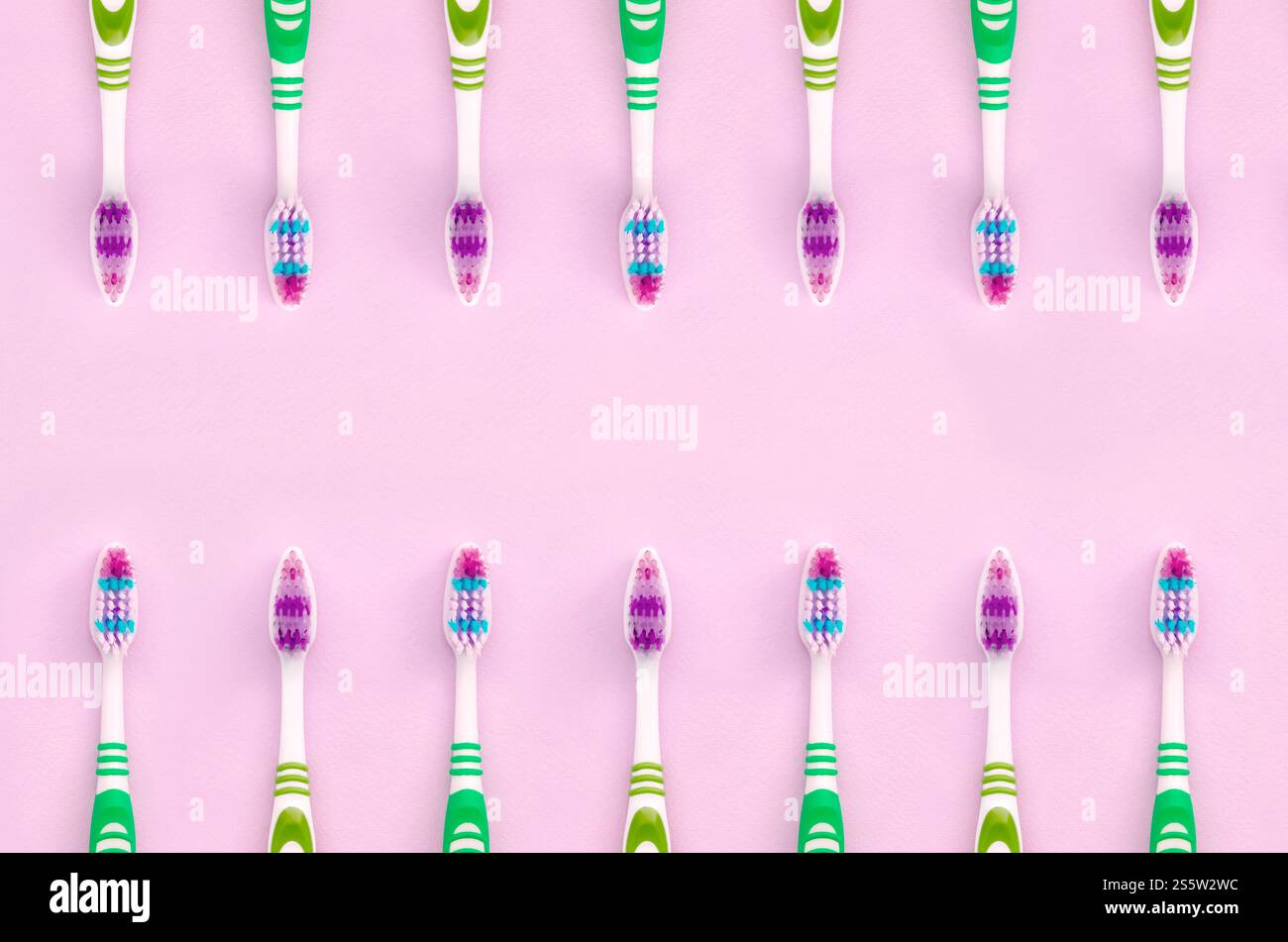 A lot of toothbrushes lie on a pastel pink background. Top view, flat ...