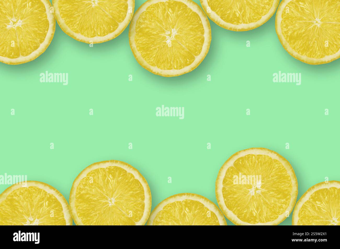 Top view of yellow lemon fruit slices on bright lime background. A ...