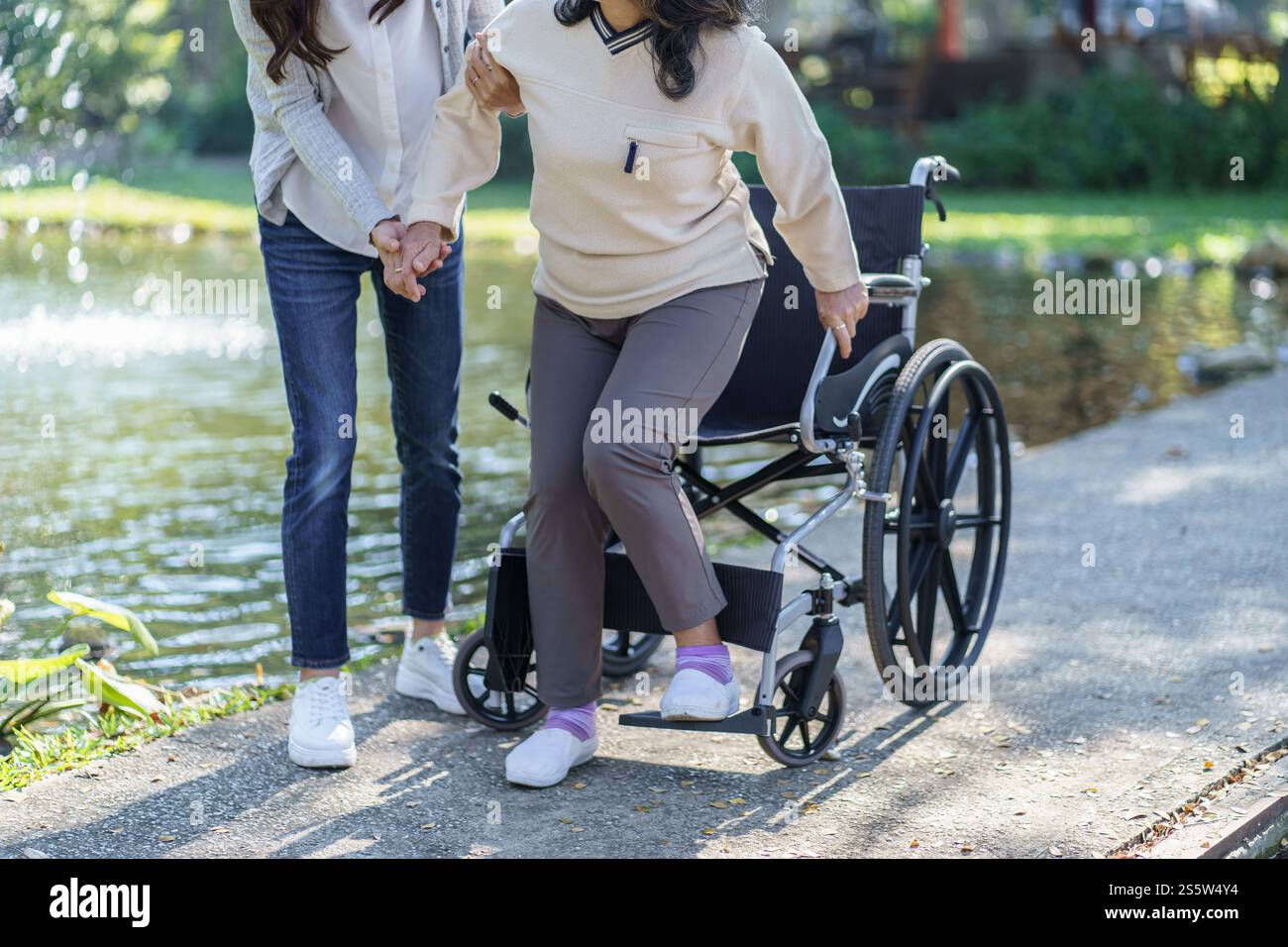 Nursing home. Young caregiver helping senior woman in wheelchair Stock ...