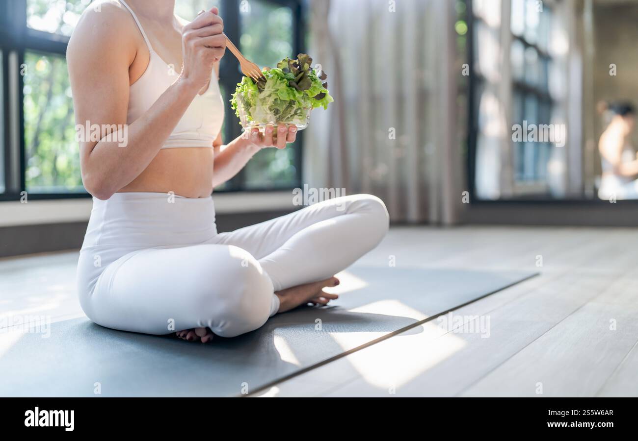 Fitness woman eating healthy salad after workout. training in yoga ...