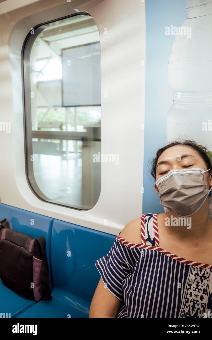 Asian adult woman subway train passanger wear face mask fall asleep ...