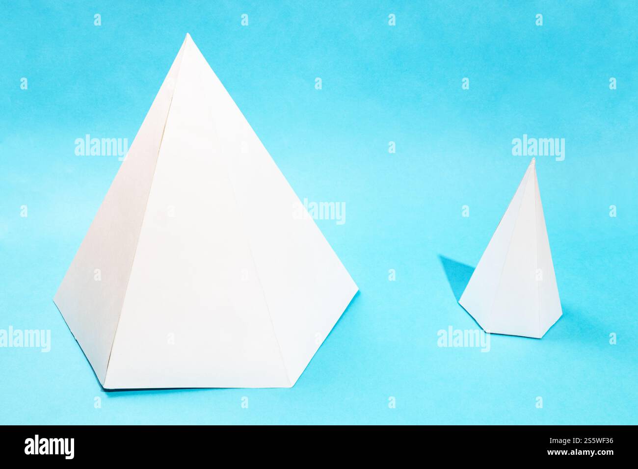 pair of different hand-crafted paper pyramids on turquoise blue ...