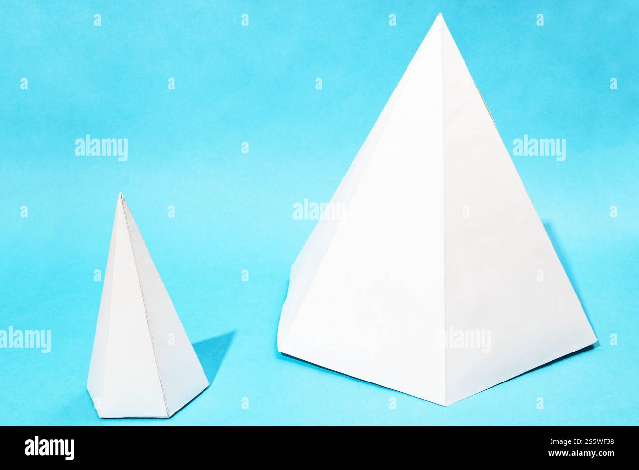 two various hand-crafted paper pyramids on turquoise blue background ...