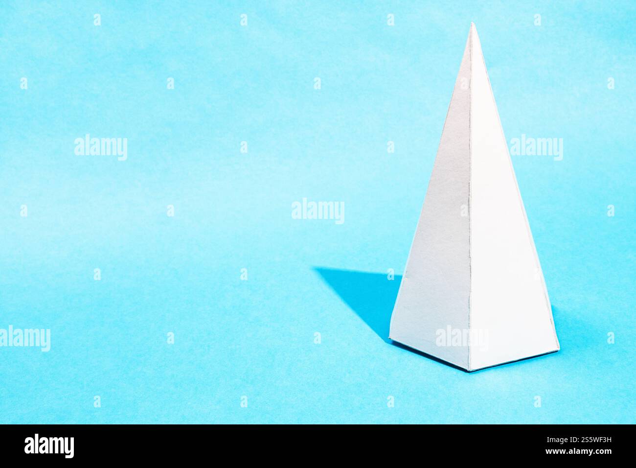 tall hand-crafted paper pyramid on turquoise blue background with ...
