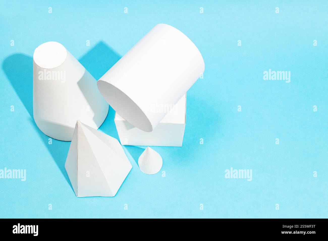 above view of various hand-crafted paper geometric shapes on turquoise ...