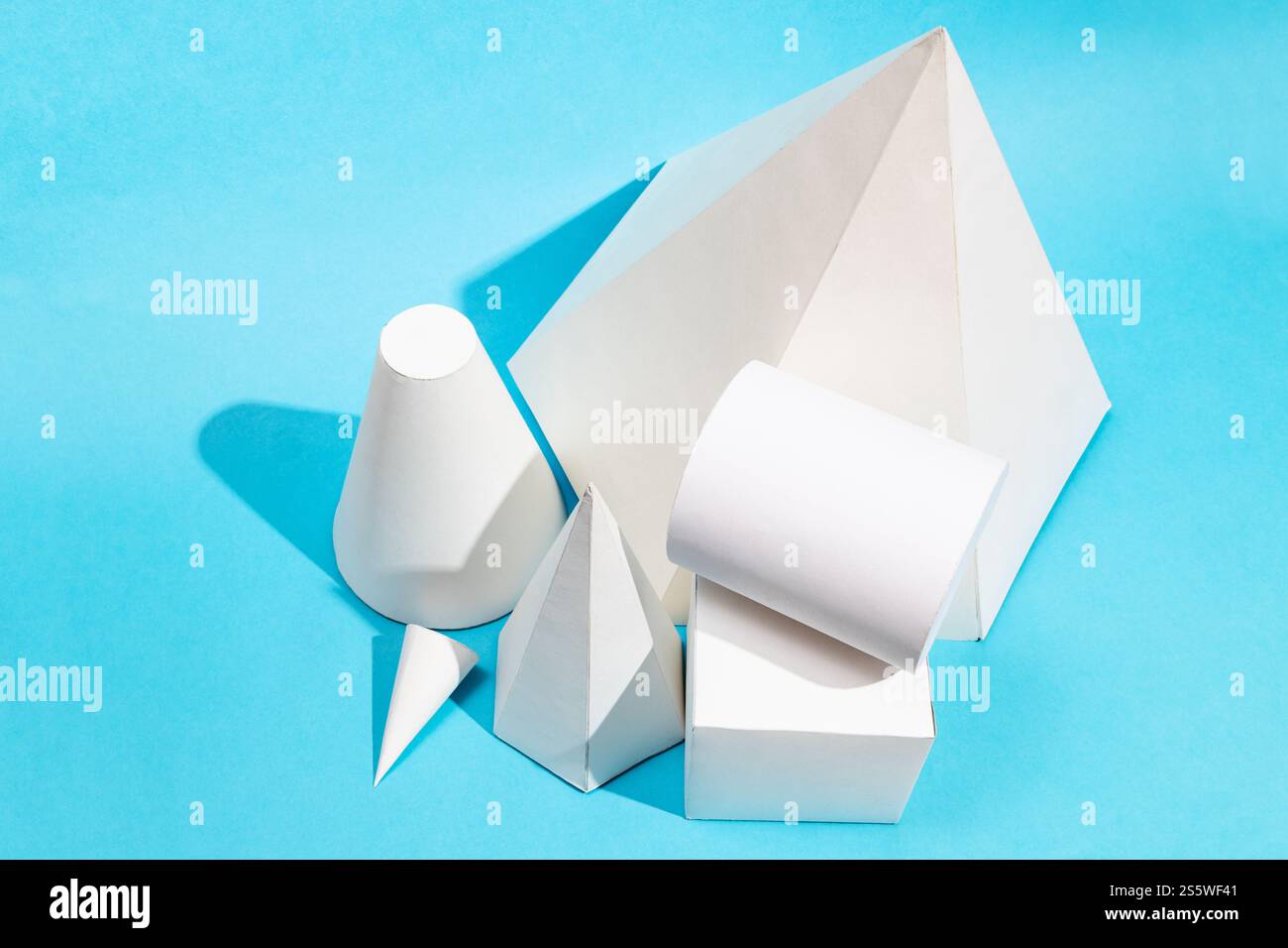 above view of different hand-crafted paper geometric forms on turquoise ...