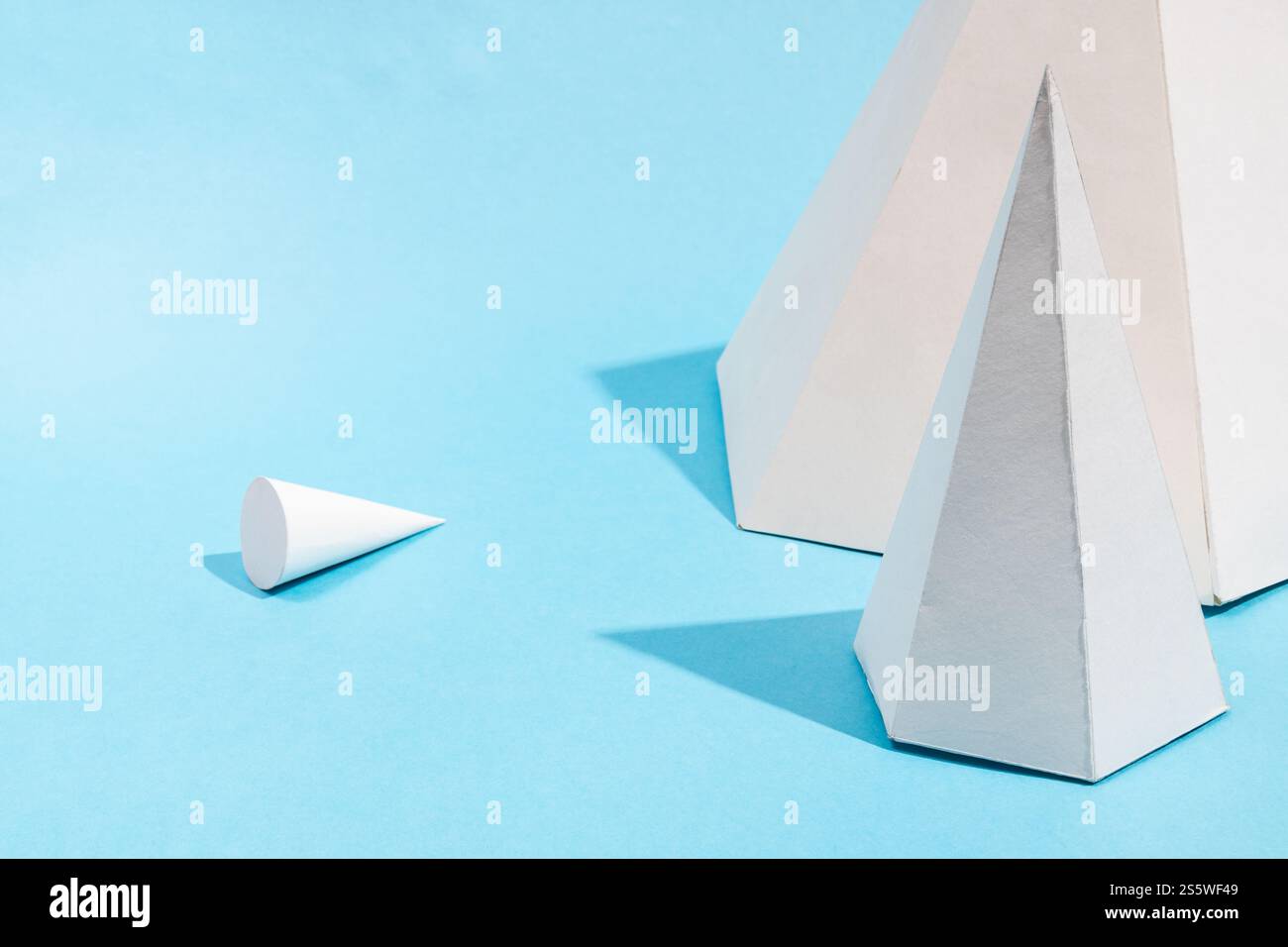 hand-crafted paper pyramids close up and lying cone top on turquoise ...