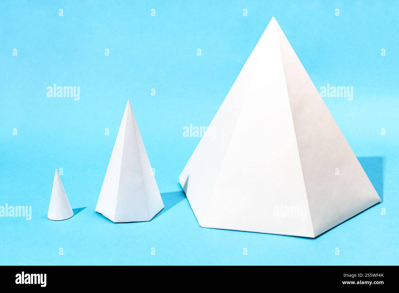 handmade various paper cone and pyramids on turquoise blue background ...
