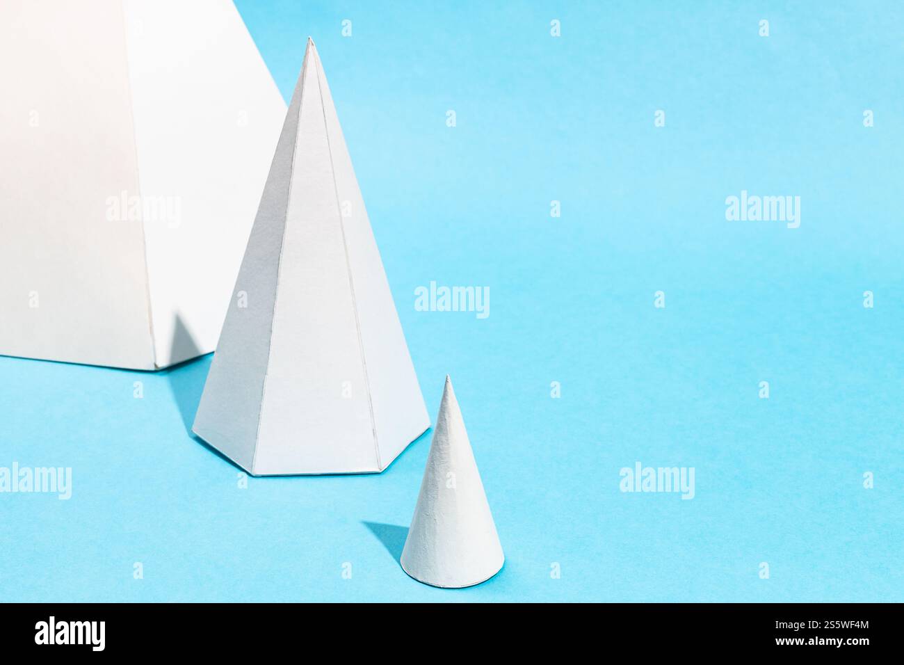 handmade different paper cone and pyramids close up on turquoise blue ...