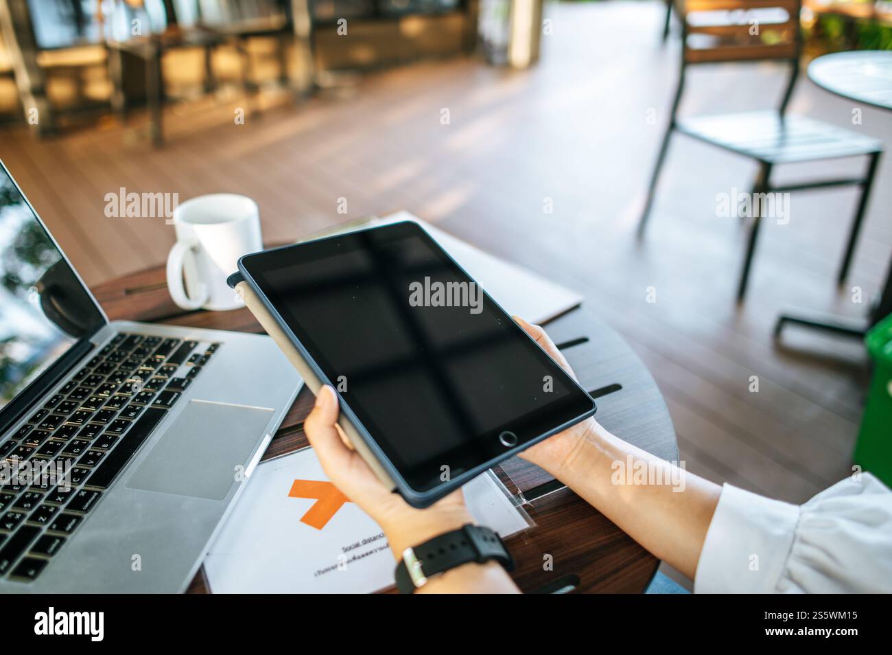 Hand holding a tablel with laptop in coffe shop Stock Photo - Alamy
