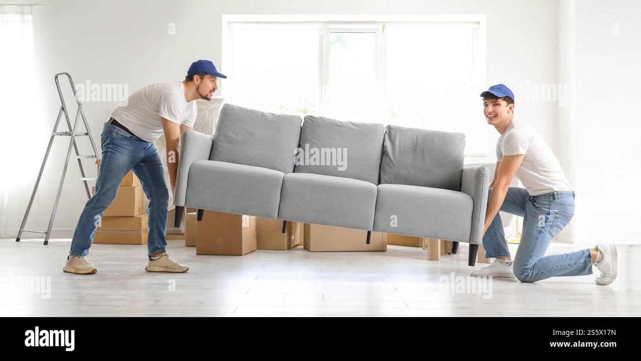 Loaders carrying sofa in room Stock Photo - Alamy