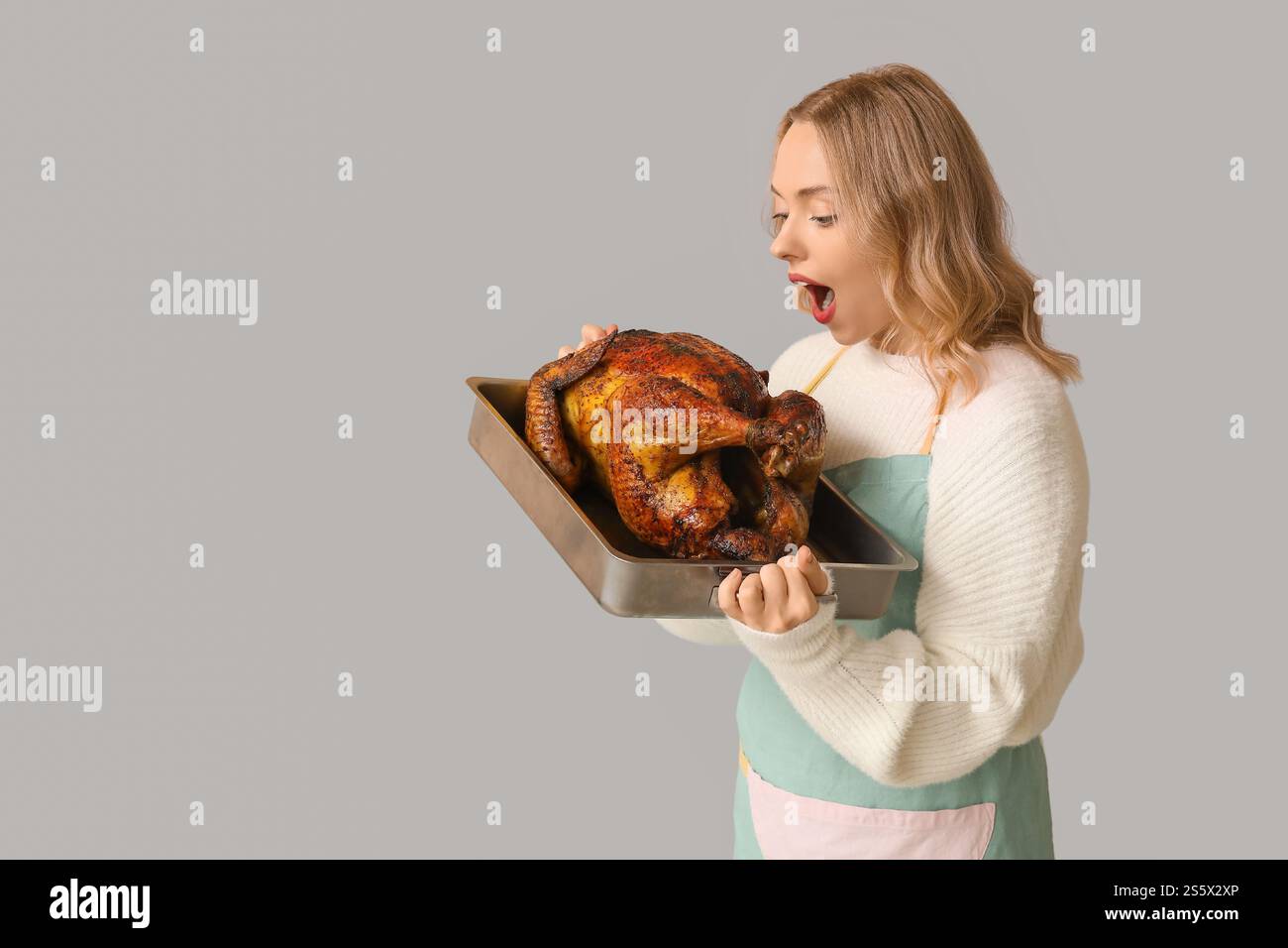 Shocked young woman with tasty baked turkey on grey background ...