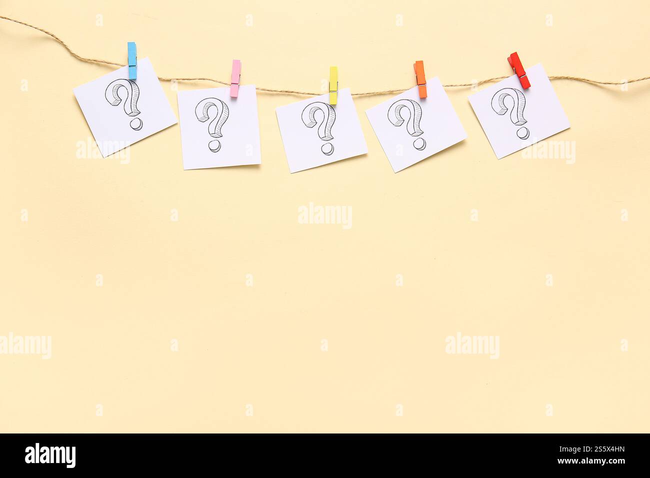 Sticky notes with question marks hanging on rope against color ...