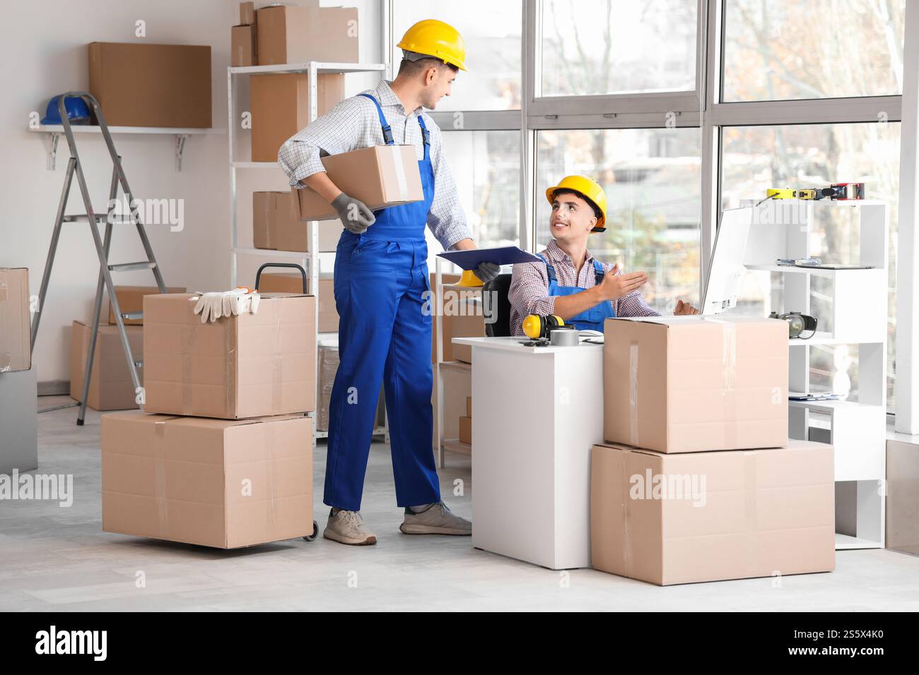 Male loaders working with computer and boxes in warehouse Stock Photo ...