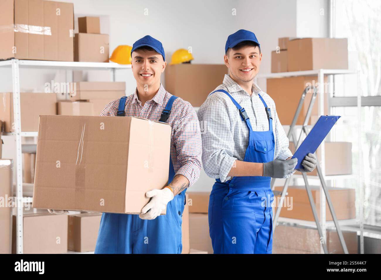 Male loaders with box and clipboard in warehouse Stock Photo - Alamy