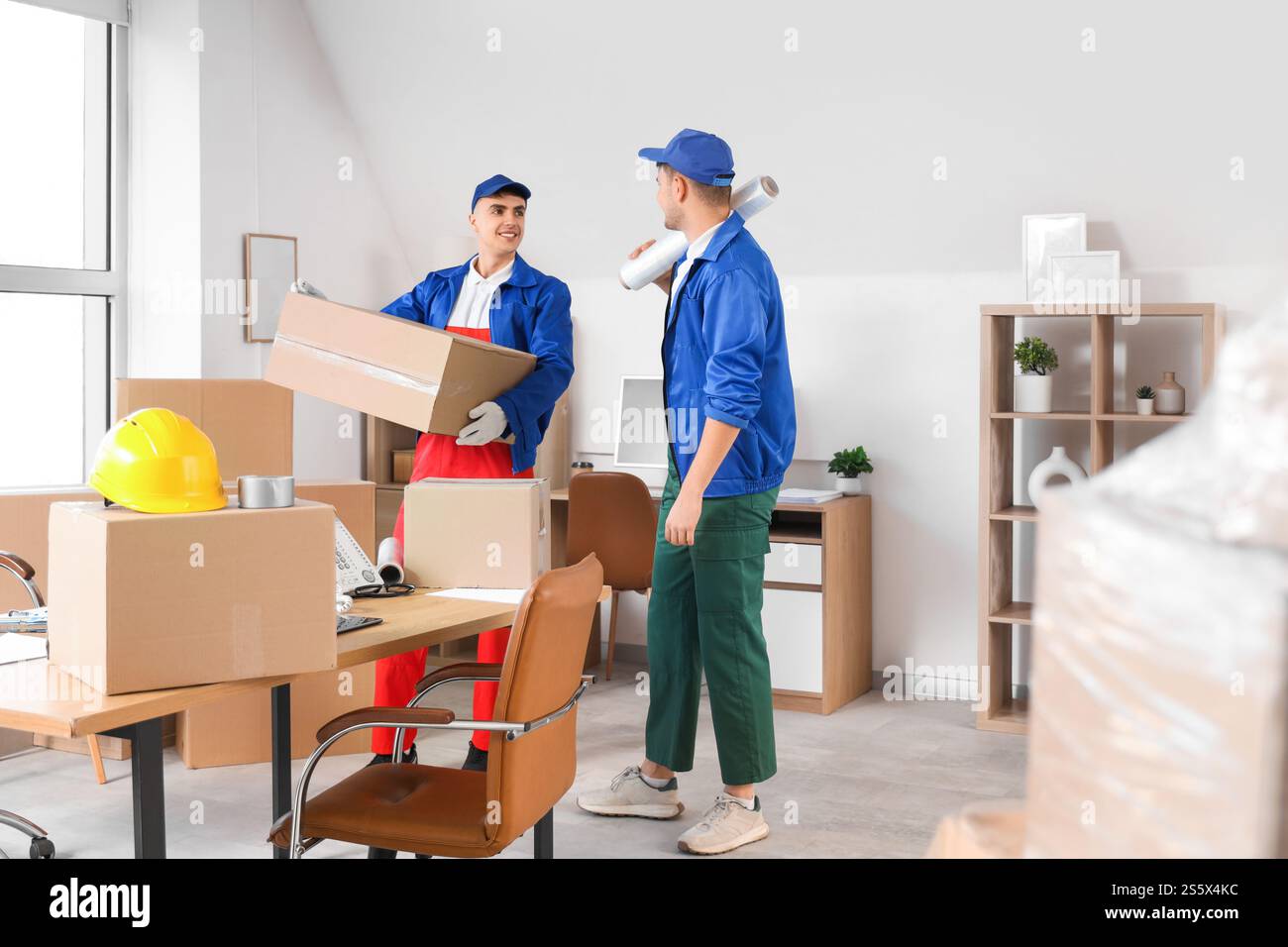 Male loaders with roll of stretch wrap and box in office Stock Photo ...