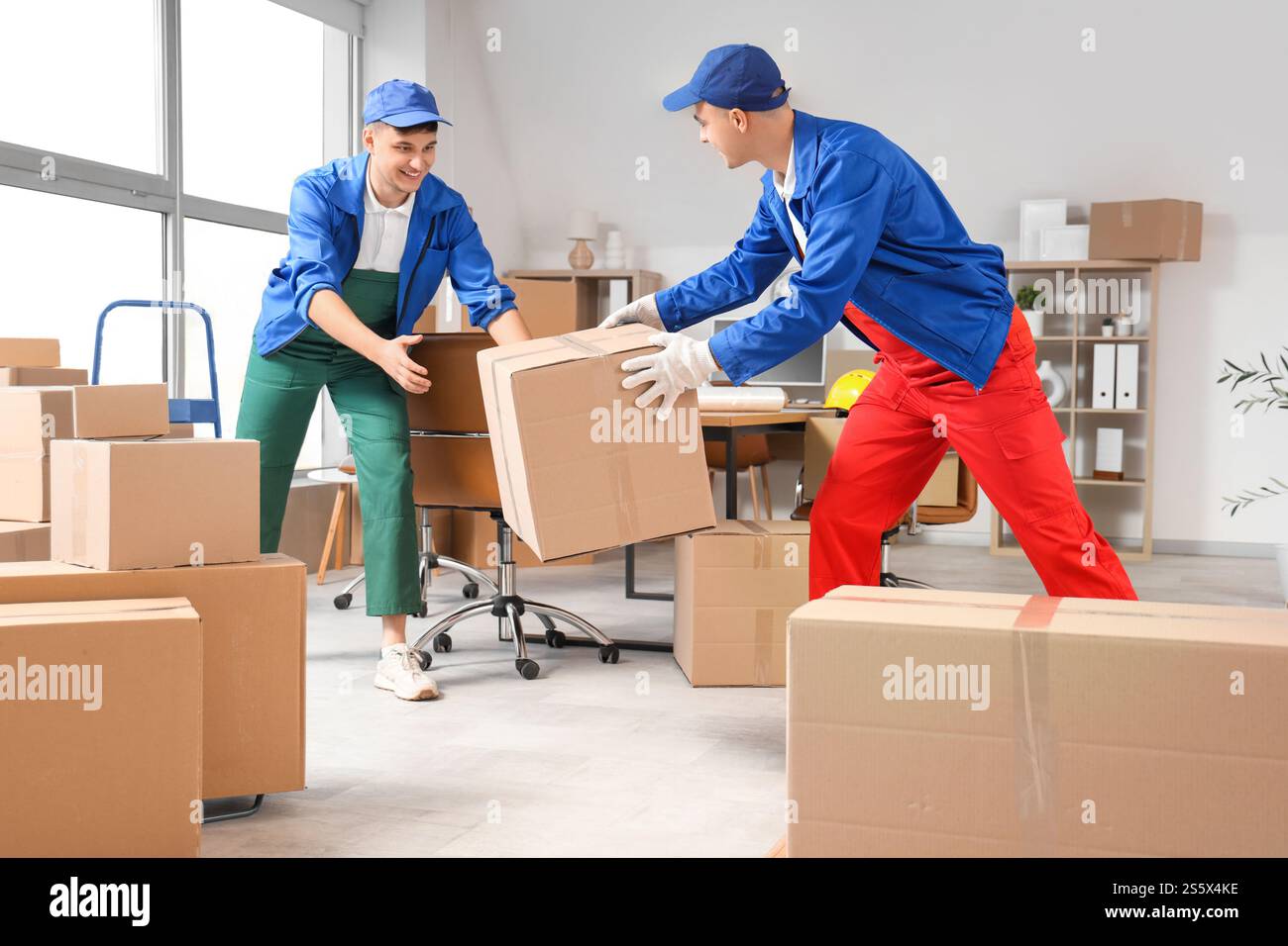 Male loaders unloading boxes in office Stock Photo - Alamy