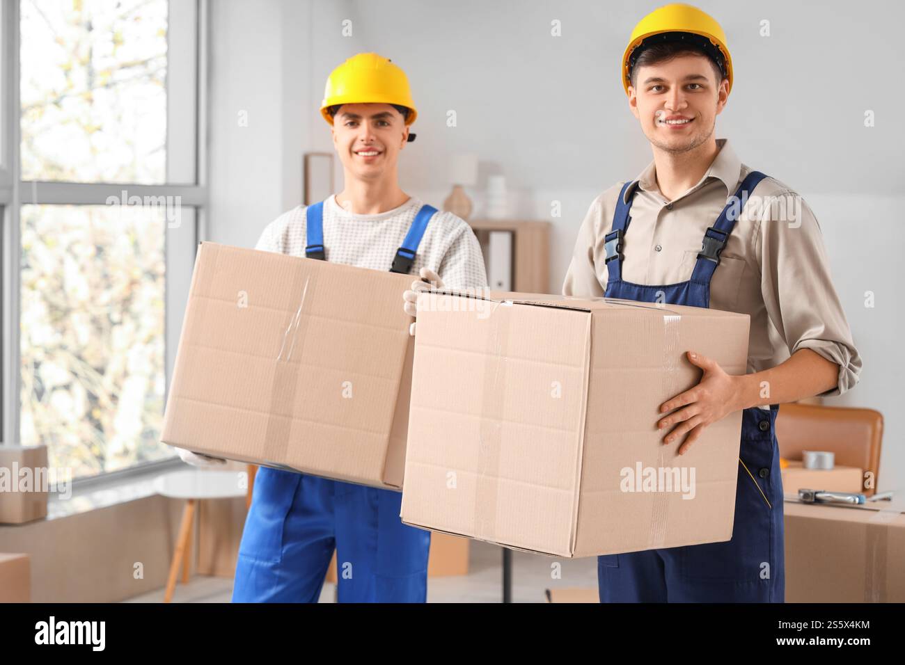 Male loaders with cardboard boxes in office Stock Photo - Alamy