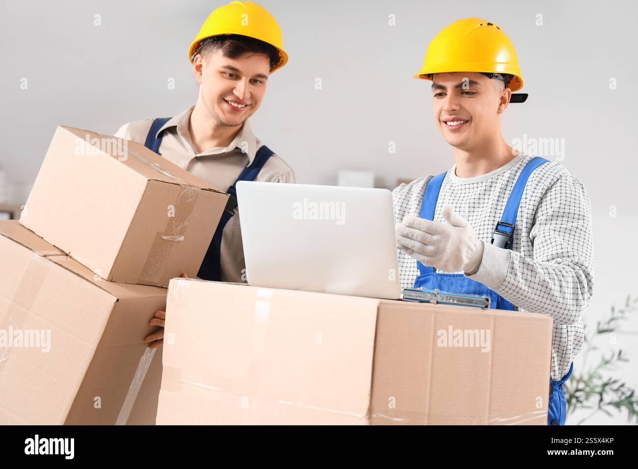 Male loaders working with laptop and boxes in office Stock Photo - Alamy
