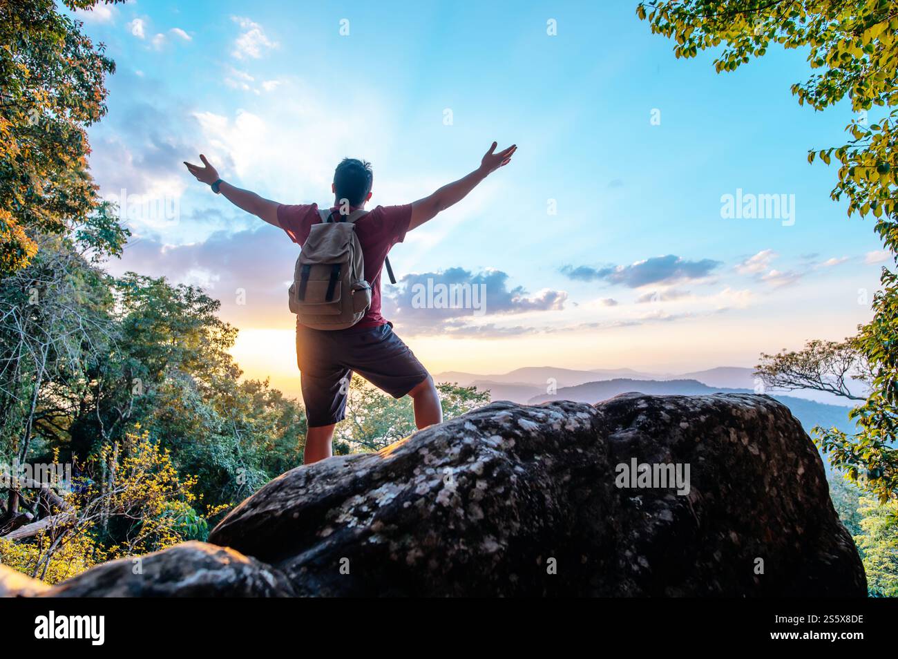 Rear view back of Young asian hiking man standing and rise-up hands ...