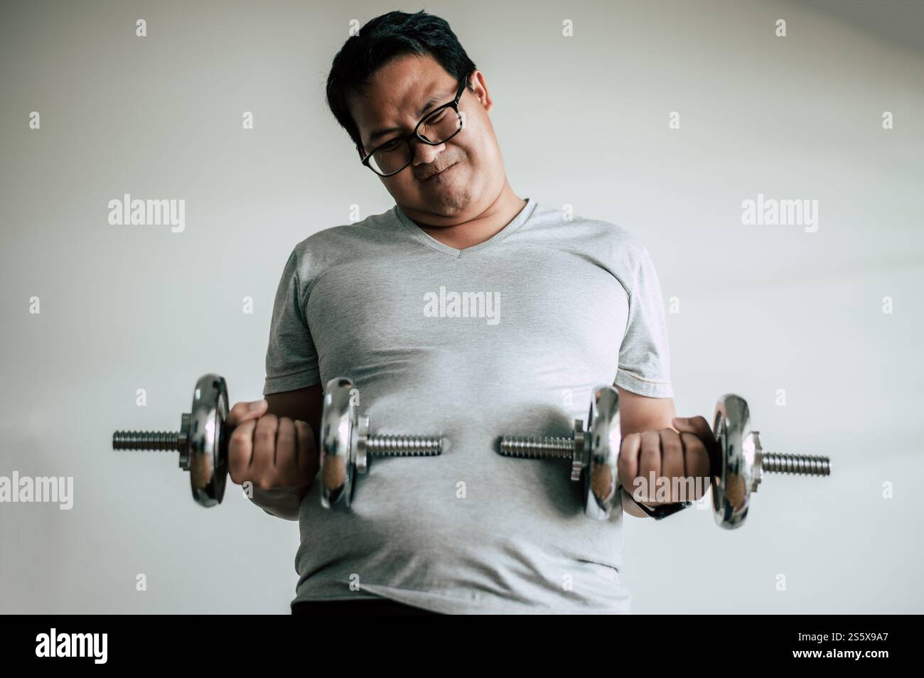 Portrait young Fat man is lifting up dumbbell in two hands to exercise ...