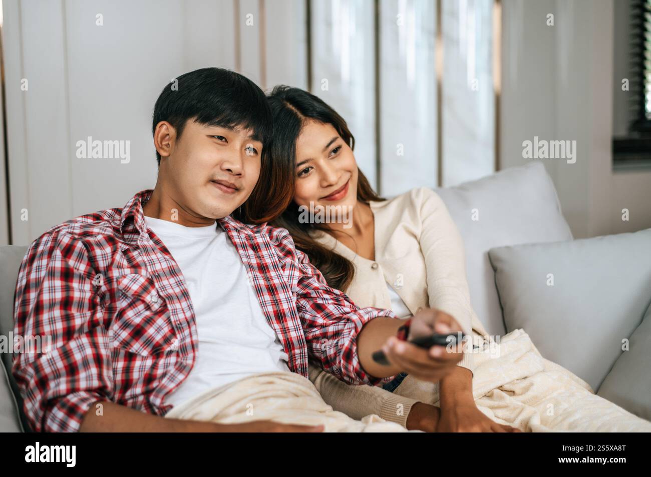 Young Asian couple watch television on sofa in new house and watch ...