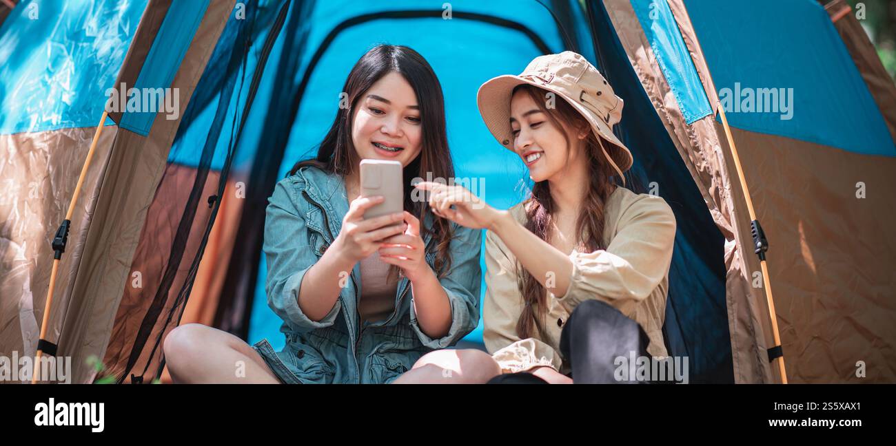 Group of young women sitting at front of camping tent in nature park ...