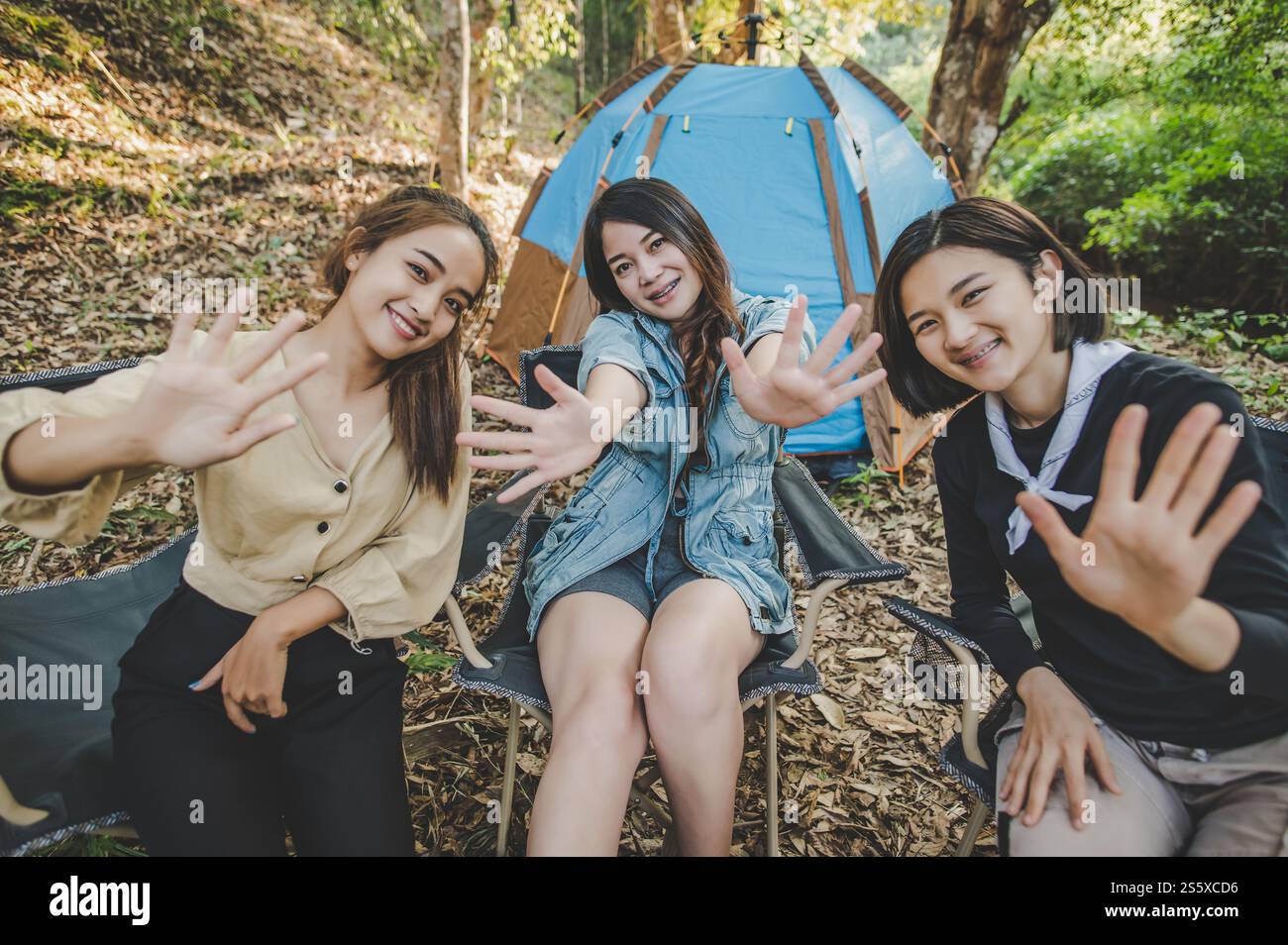 Group of pretty women sitting on camping chair at front of tent for ...
