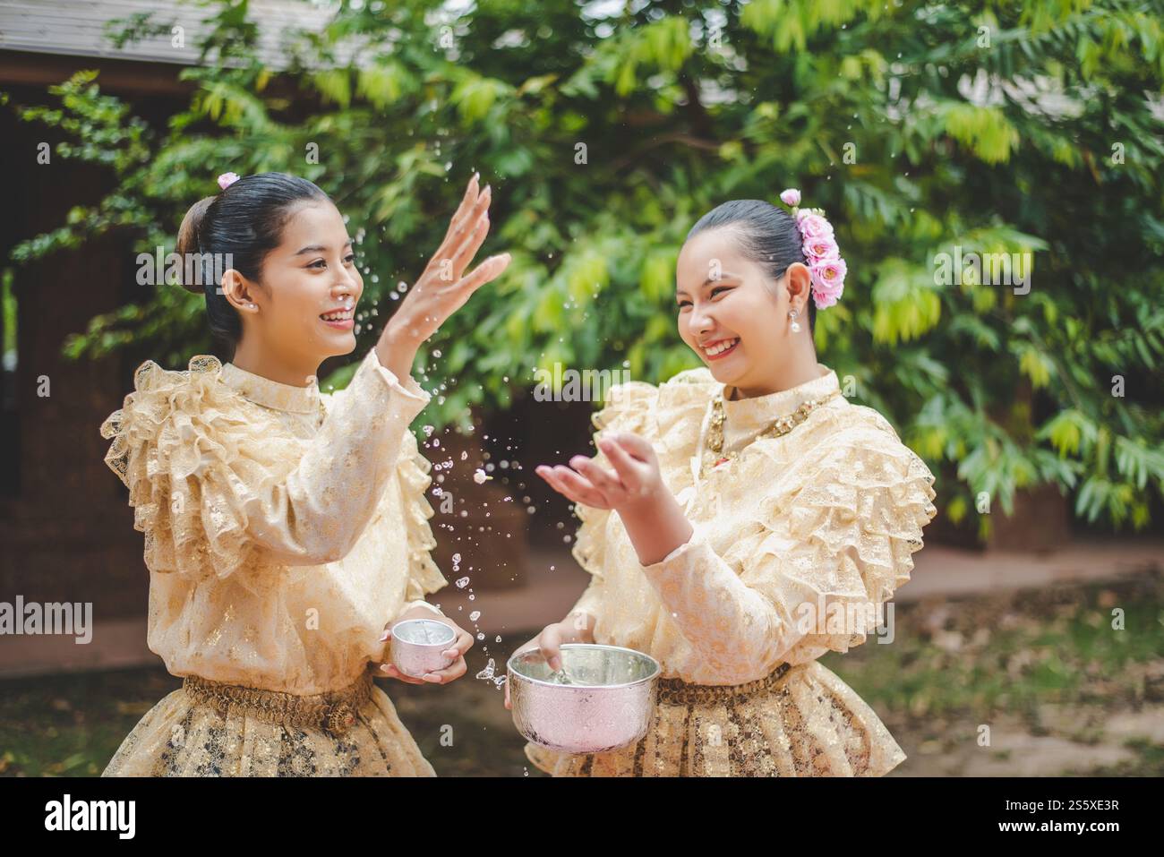 Young smiling women dress in beautiful Thai costumes splashing water in temples and preserve the ...