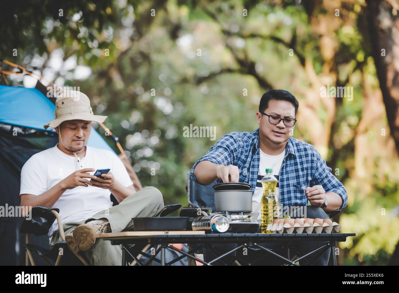 Portrait of Asian relaxed man using smartphone and waiting for his ...