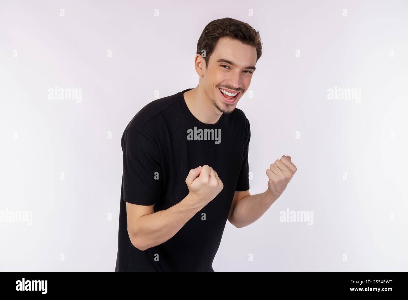 Portrait of happy joyful young man standing doing winner gesture ...