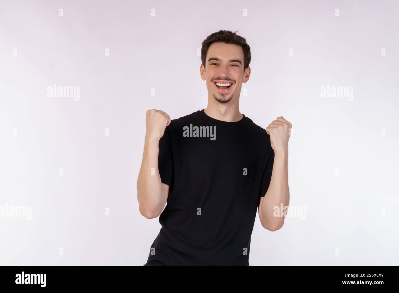 Portrait of happy joyful young man standing doing winner gesture ...