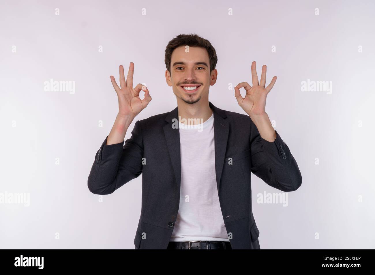 Portrait of happy young handsome businessman doing ok sign with hand ...