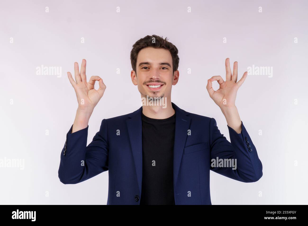 Portrait of happy young handsome businessman doing ok sign with hand ...