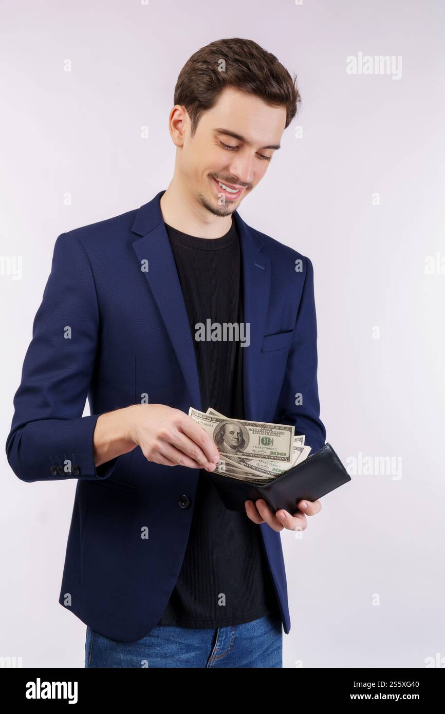 Excited young man putting banknotes into wallet isolated white studio ...