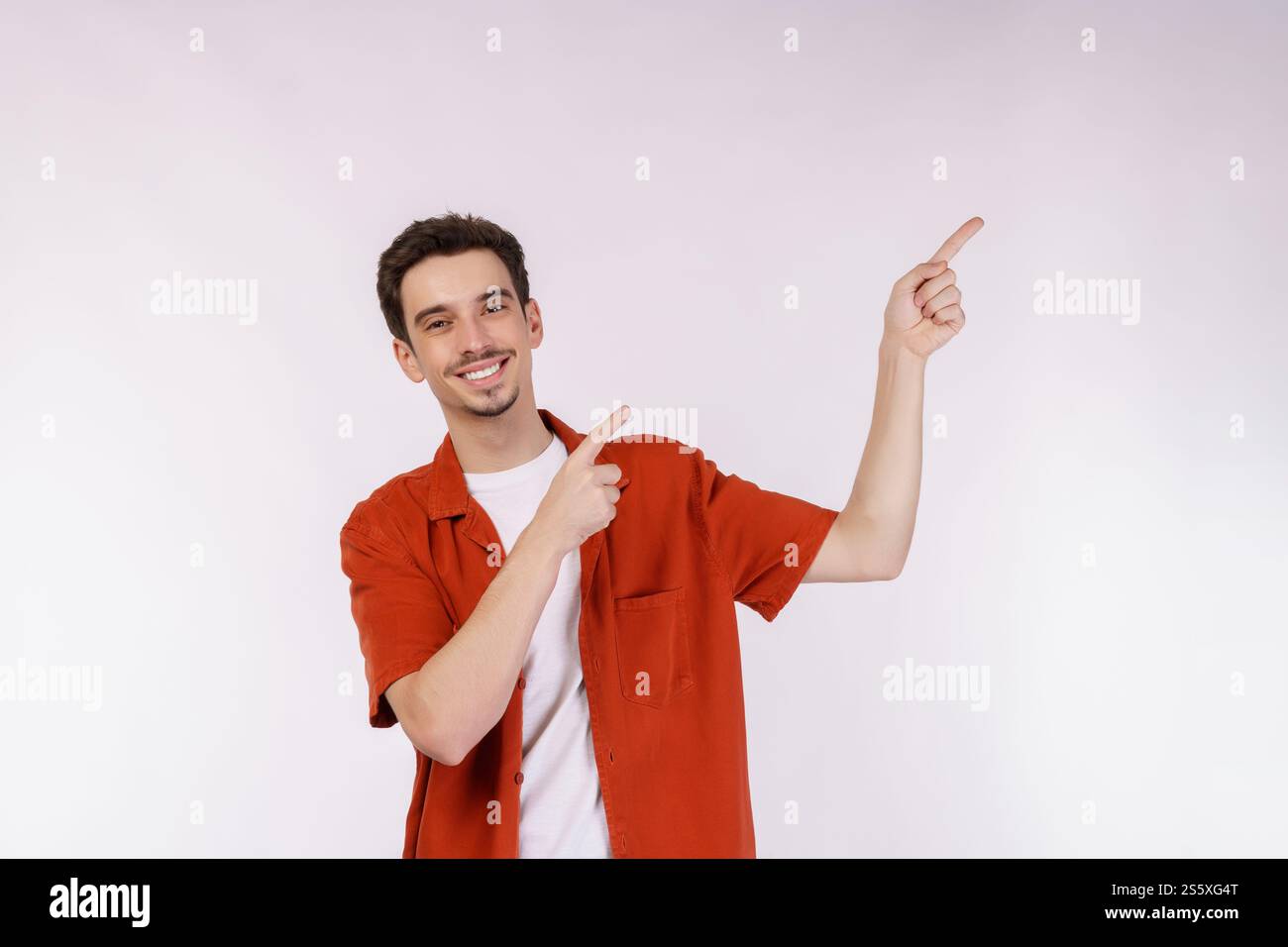 Portrait of young man pointing fingers at copy space isolated on white ...
