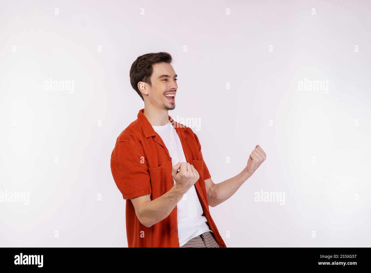 Portrait of happy joyful young man standing doing winner gesture ...